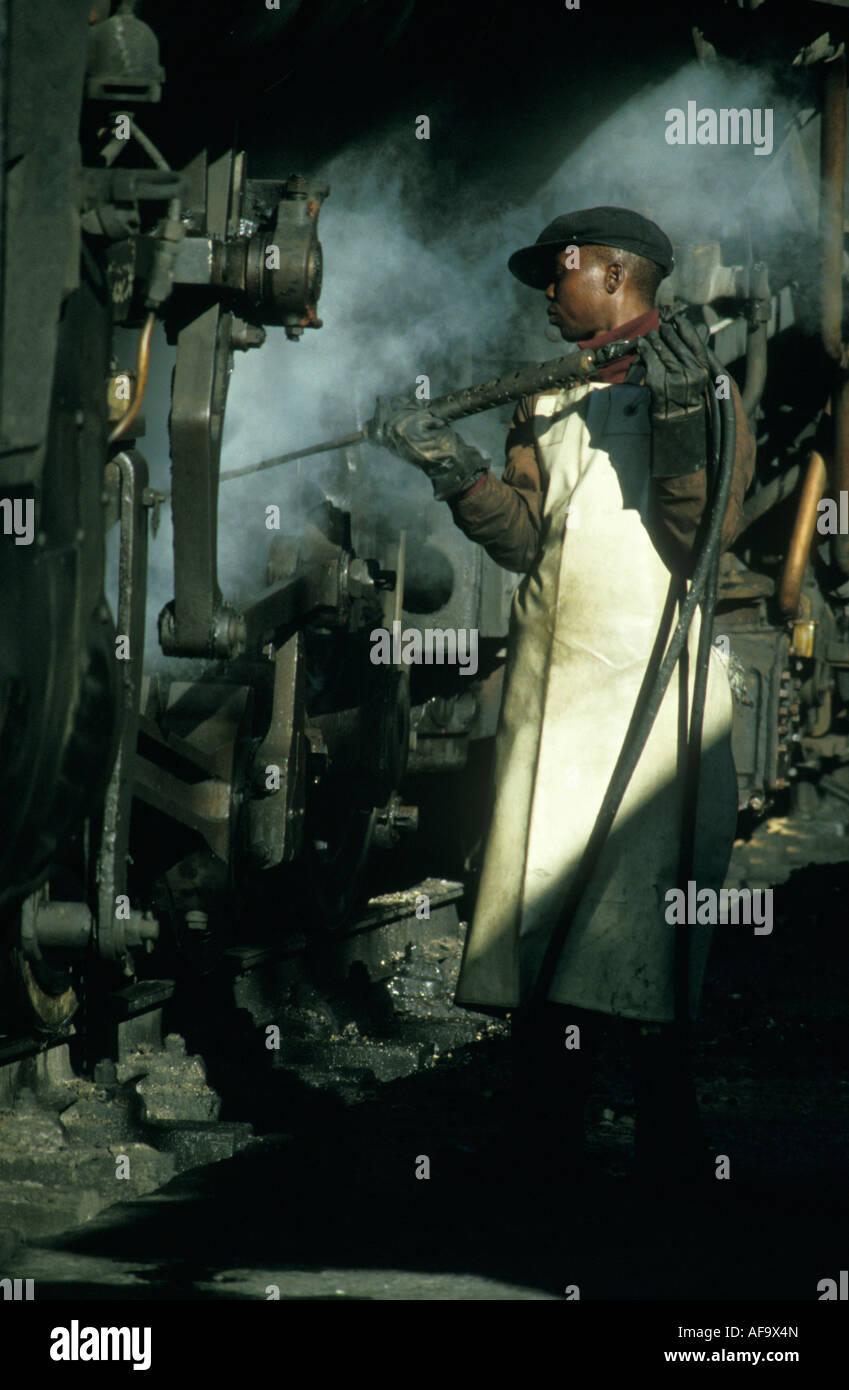 A railway mechanic cleaning the steam engine using a high pressure ...