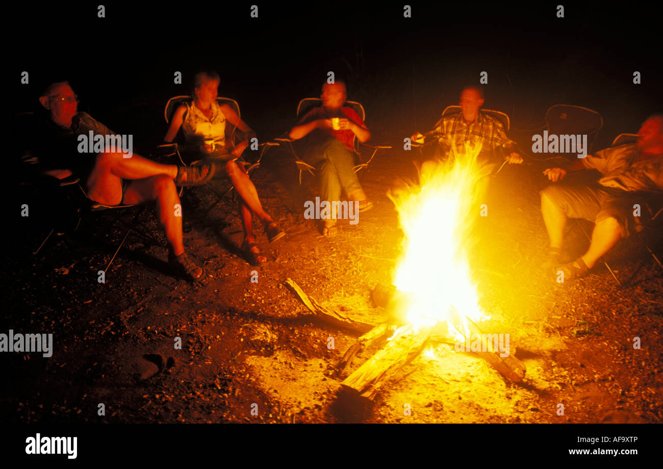 A group of campers relaxing around a blazing campfire at night Kruger ...