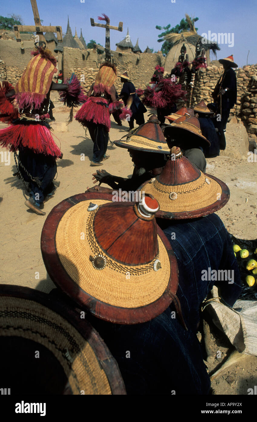 Dogon men wearing traditional hats watching dancers near Bandiagara ...