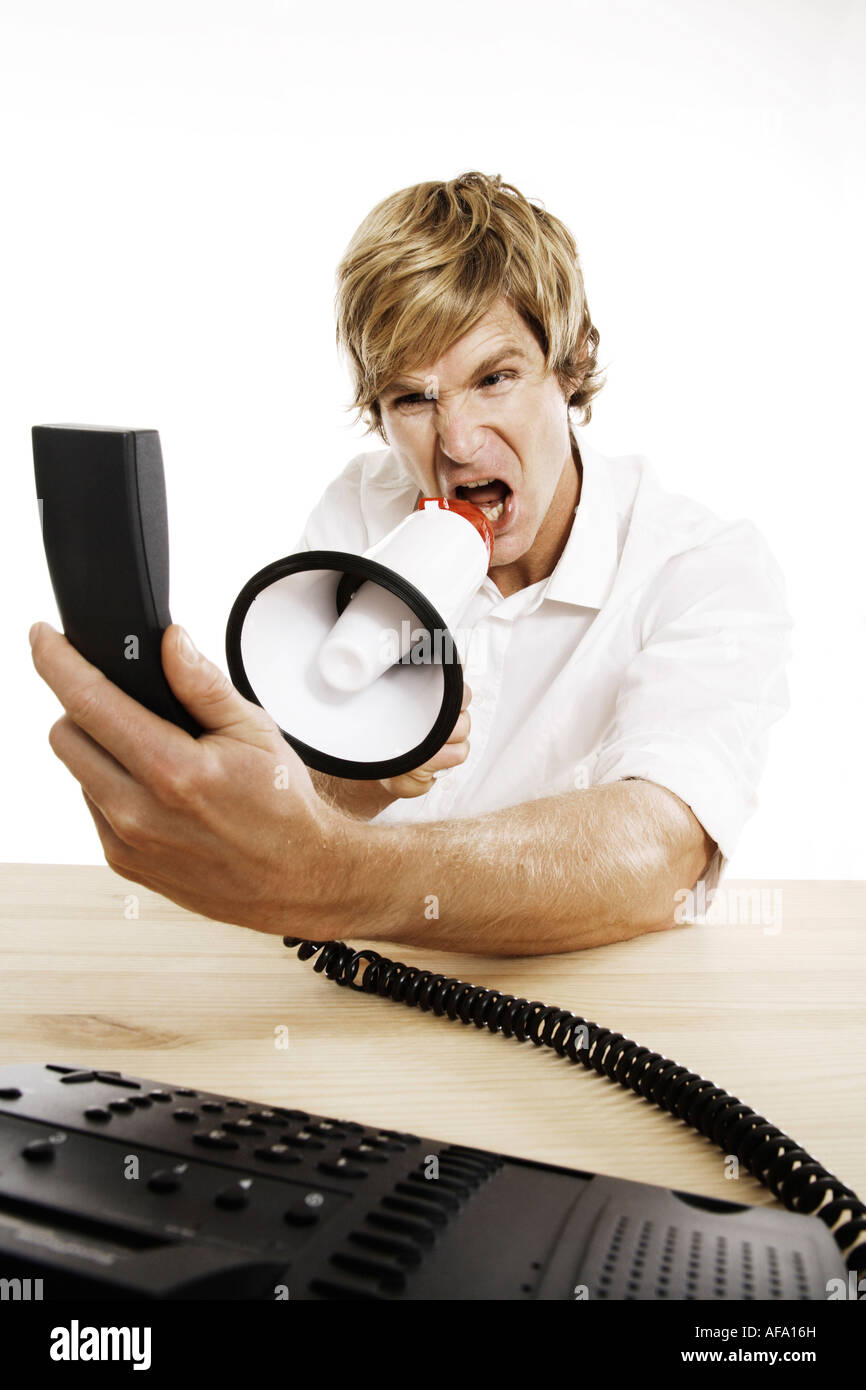 Man holding phone, shouting in megaphone Stock Photo - Alamy