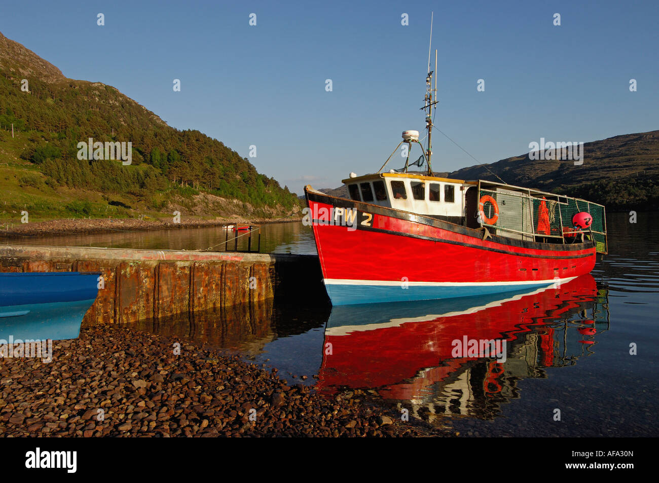 Red painted fishing boat sits at the slipway at Shieldaig Torridon ...