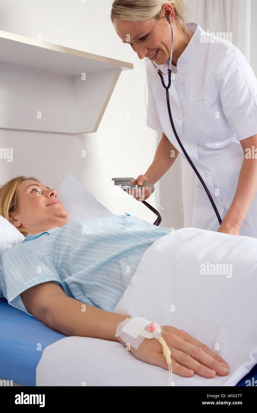 Nurse checking blood pressure of female patient Stock Photo - Alamy