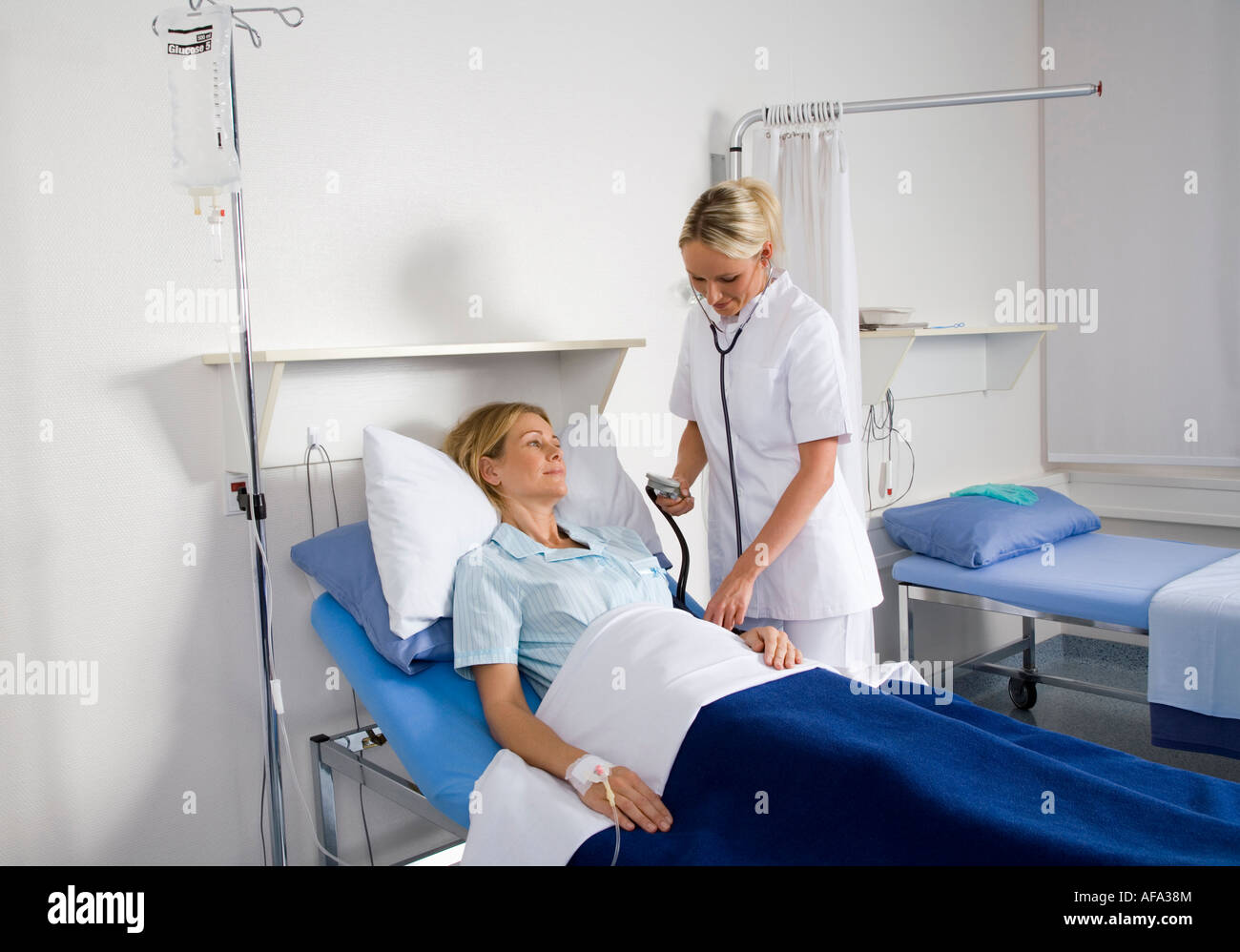 Nurse checking blood pressure of female patient Stock Photo - Alamy