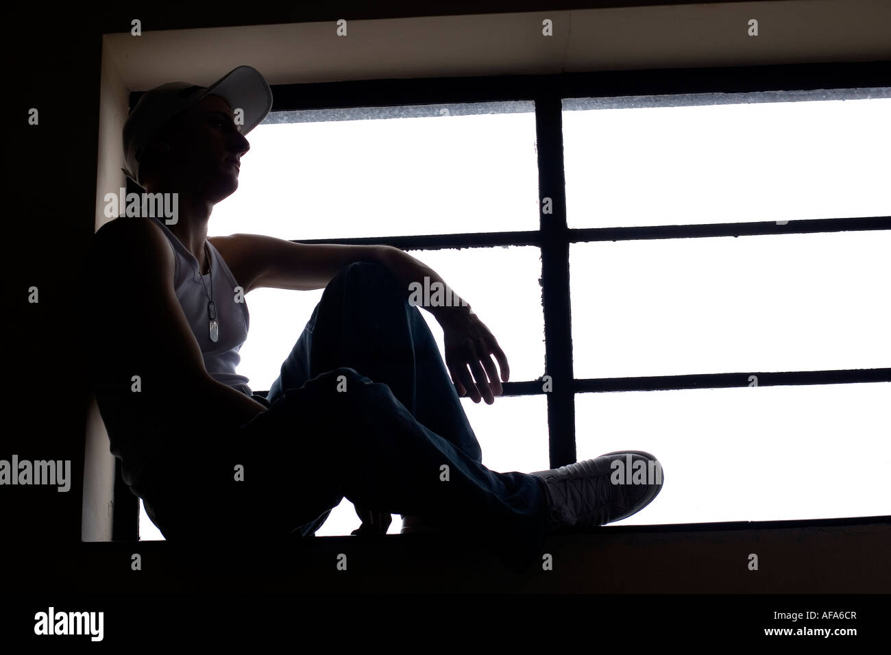 Silhoette of youth sitting on window ledge Stock Photo - Alamy