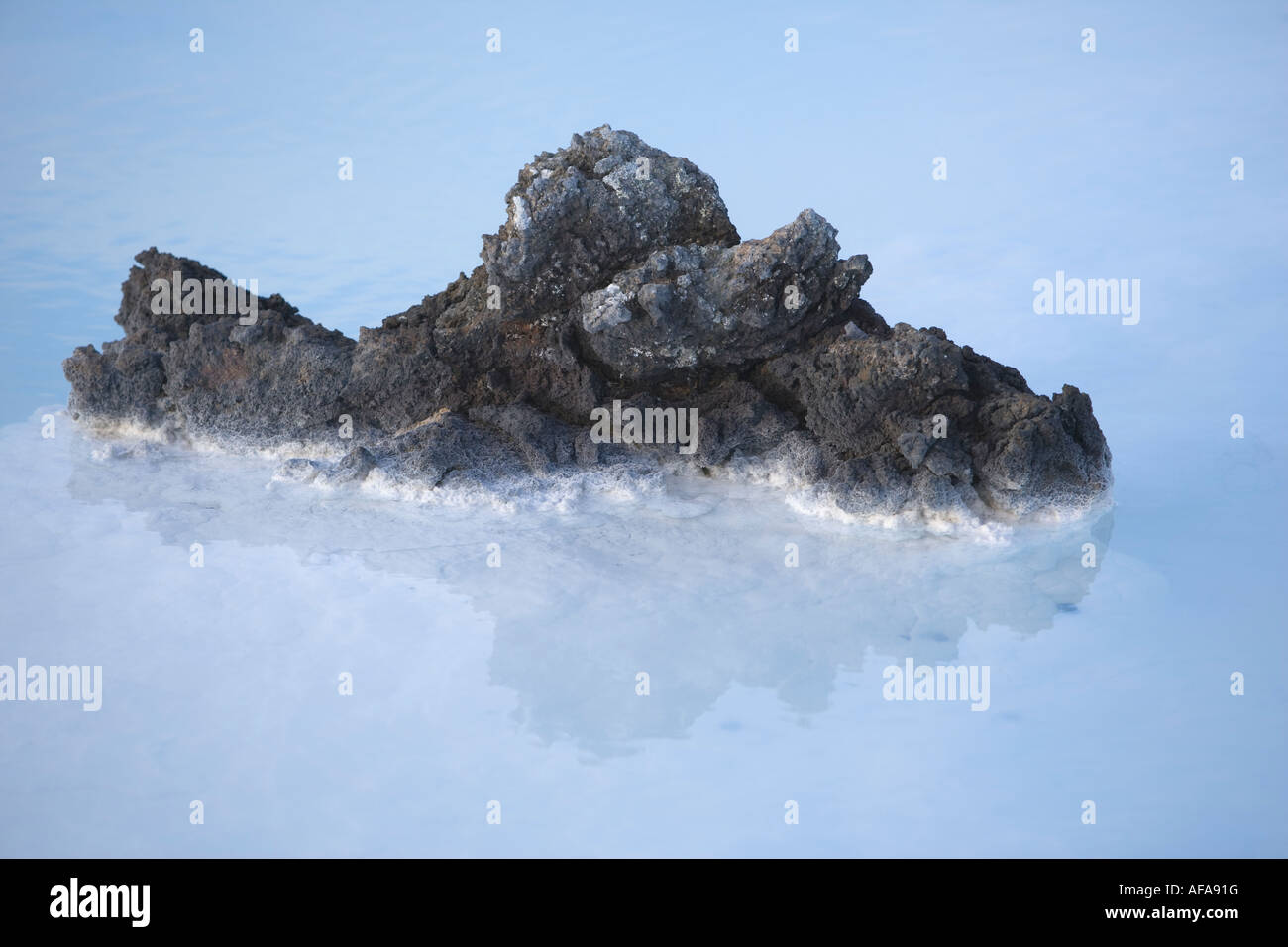 A volcanic rock in a lagoon of blue water near a geothermal spring in ...