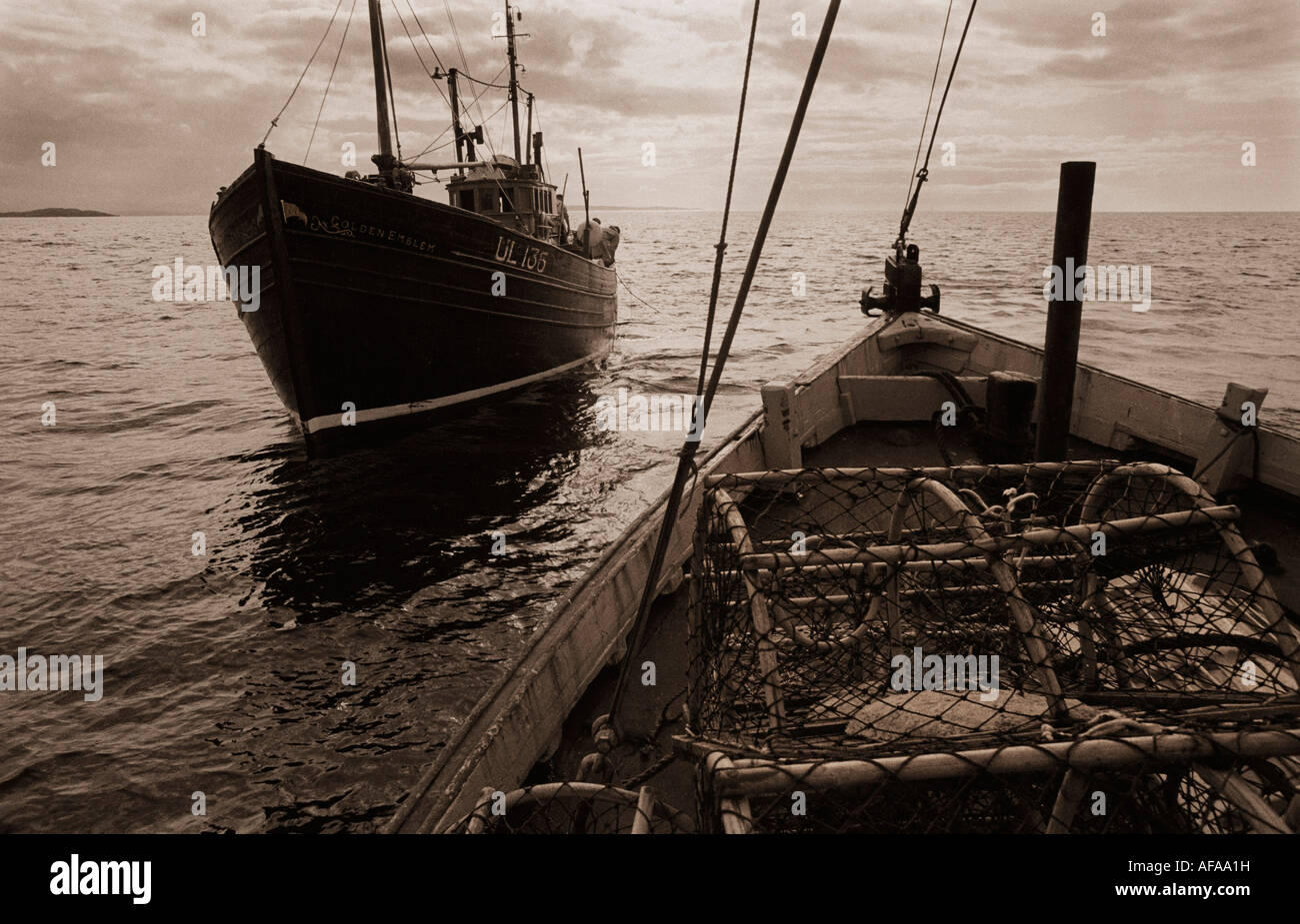 Sepia tinted monochrome shot of fishing boats meeting out in the open ...