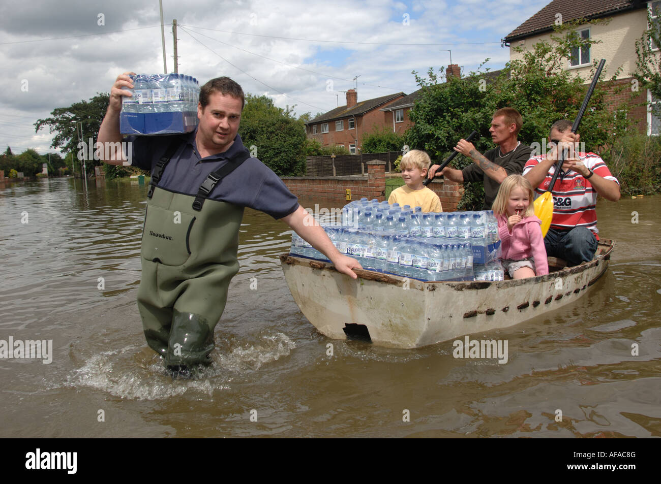 Family use a boat to deliver drinking water to neighbours during floods ...