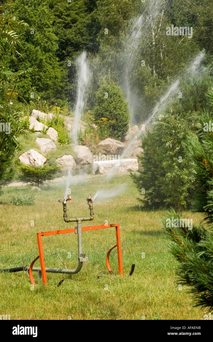 Water double sprinkler irrigating grass lawn in garden Stock Photo - Alamy