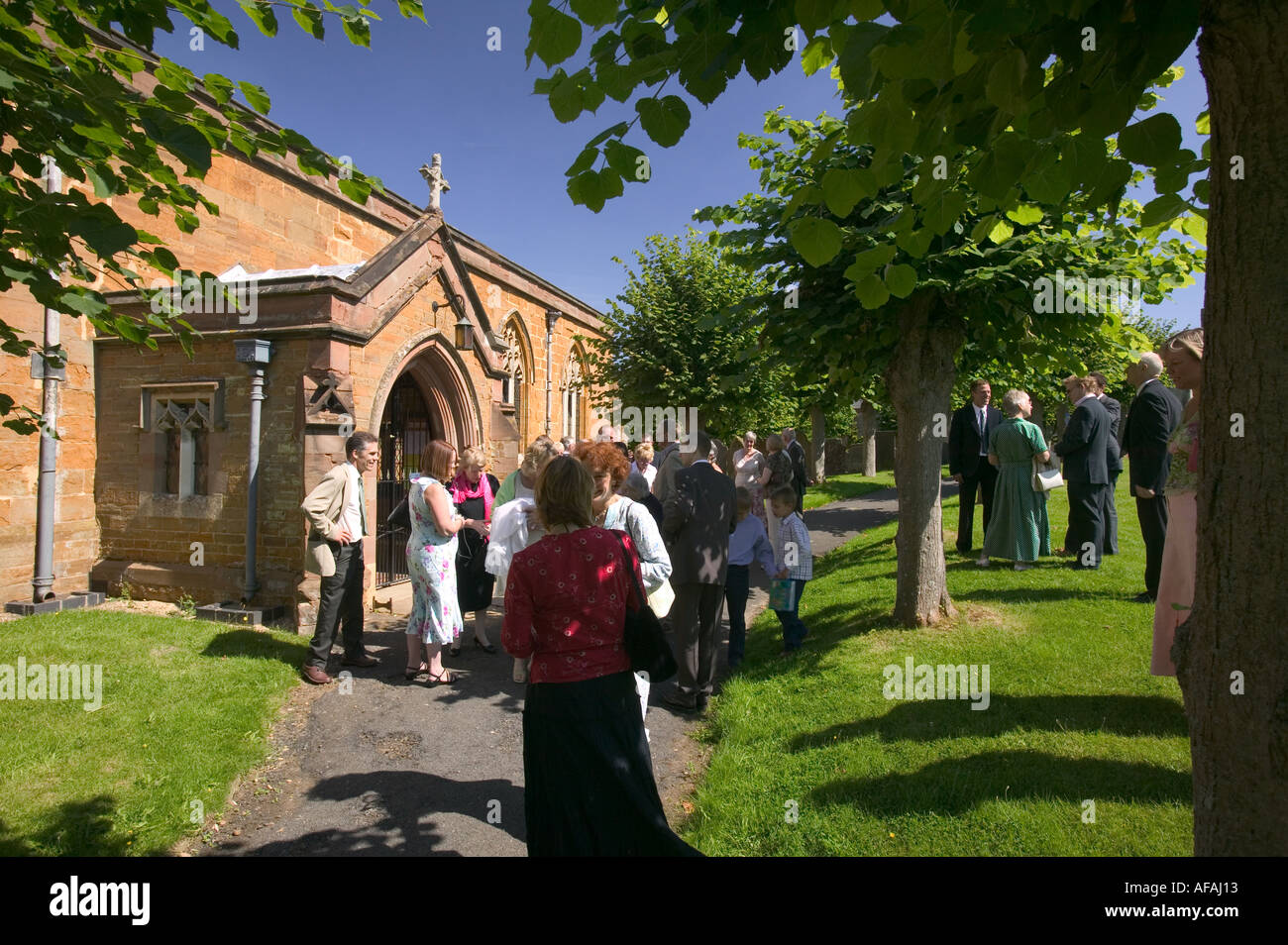 a christening party outside the ancient sandstone church in Long buckby ...