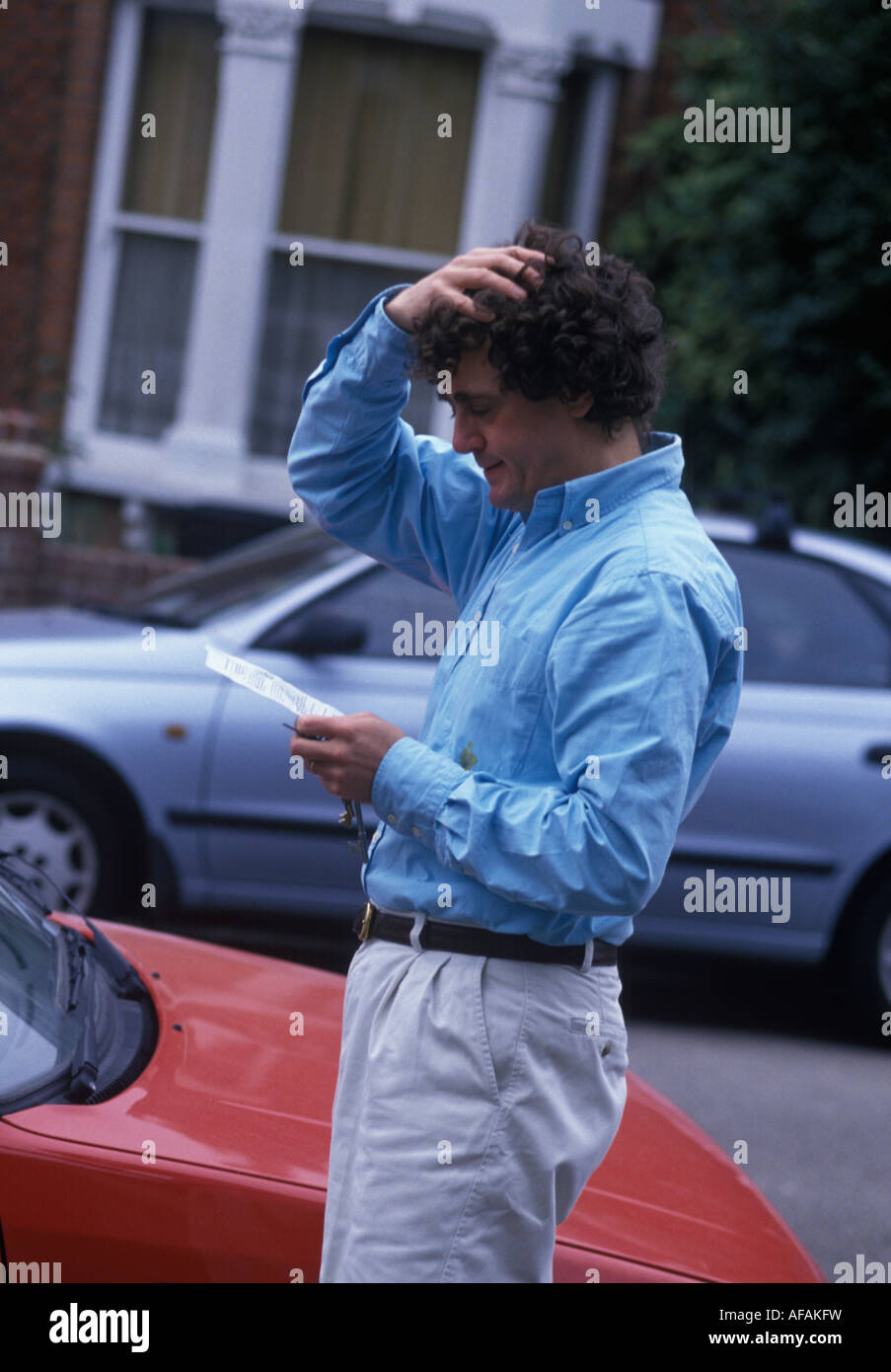 man looking at notice under his windscreen wiper Stock Photo - Alamy