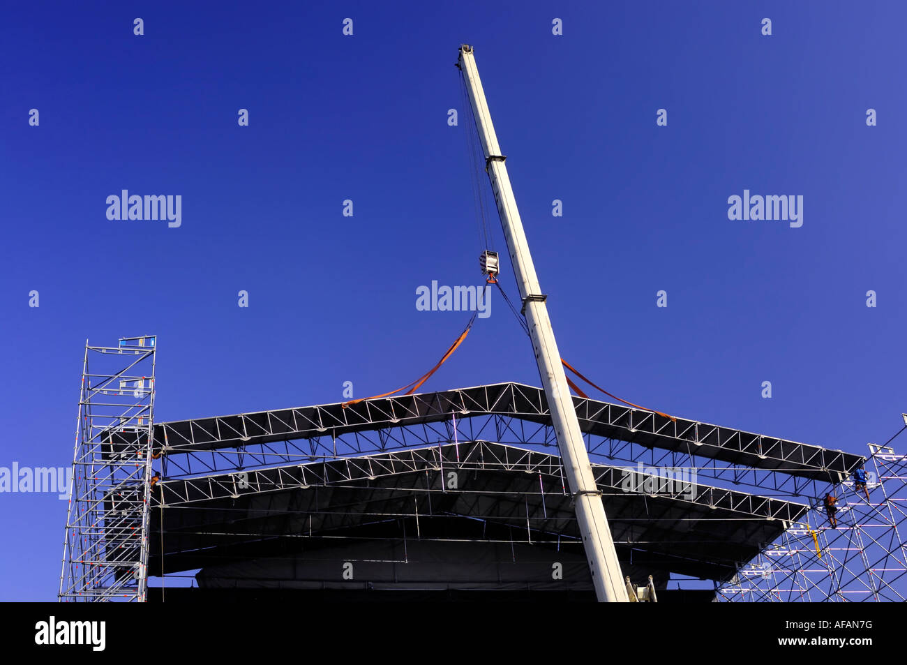 Crane on a construction site lifting a metal roof truss Stock Photo - Alamy