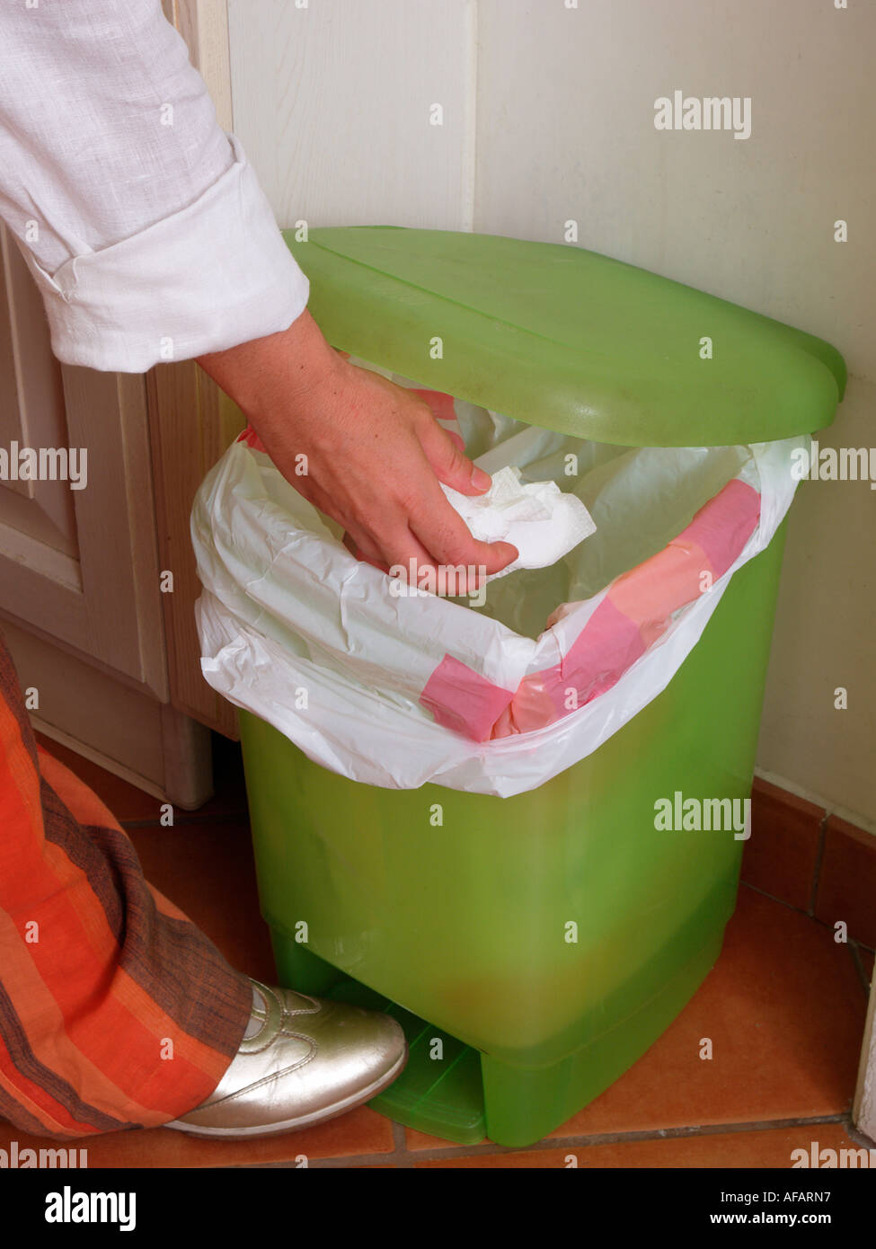person throwing away rubbish into green rubbish bin Stock Photo - Alamy
