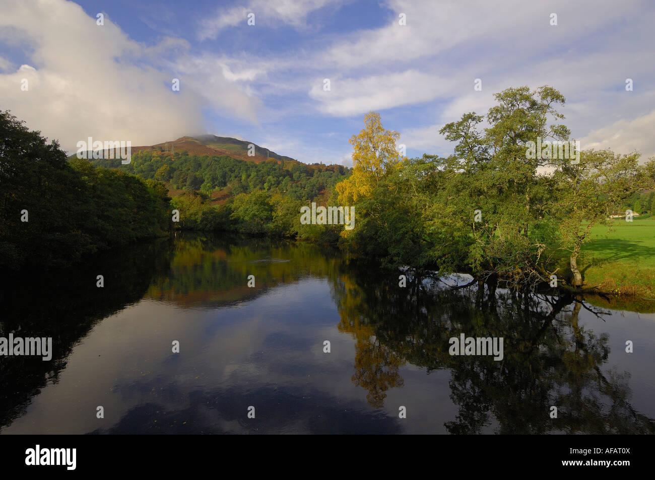 Quiet and calm River Lochay runs between tree lined banks under a soft ...