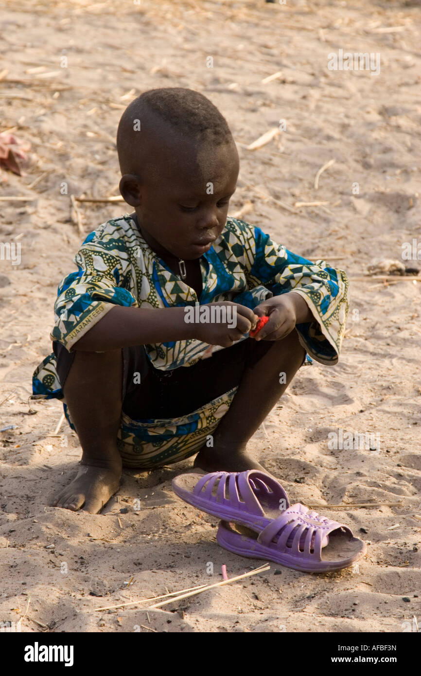 Poor african child plays in the sand in his village in Senegal, Gambia ...