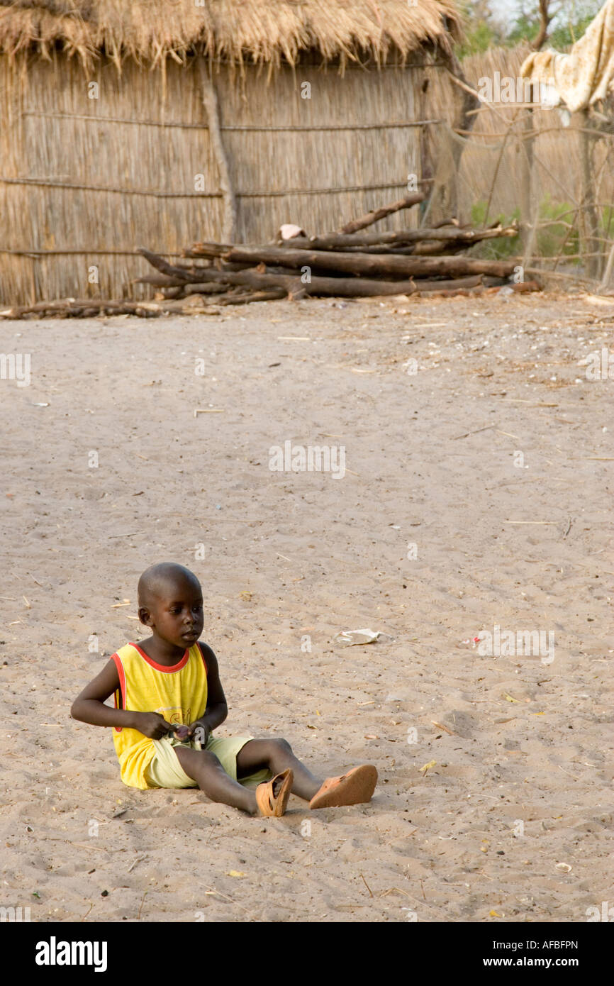 Poor child sits in the sand in a village in Senegal Stock Photo - Alamy