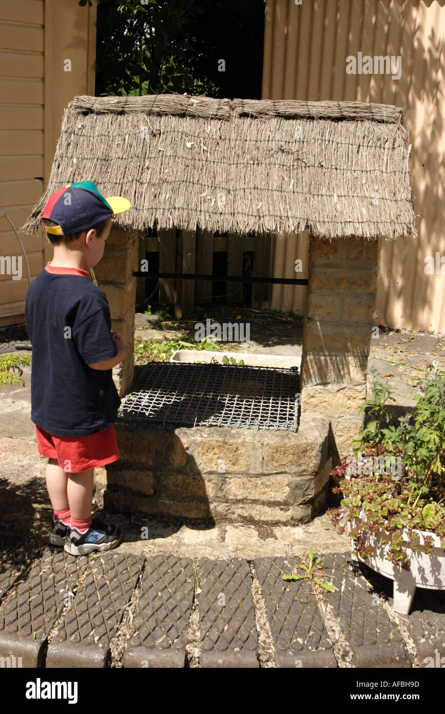 Small boy looks down a wishing well Stock Photo - Alamy