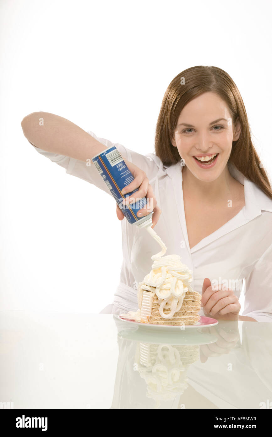 Young woman spraying cream on cake, portrait Stock Photo - Alamy