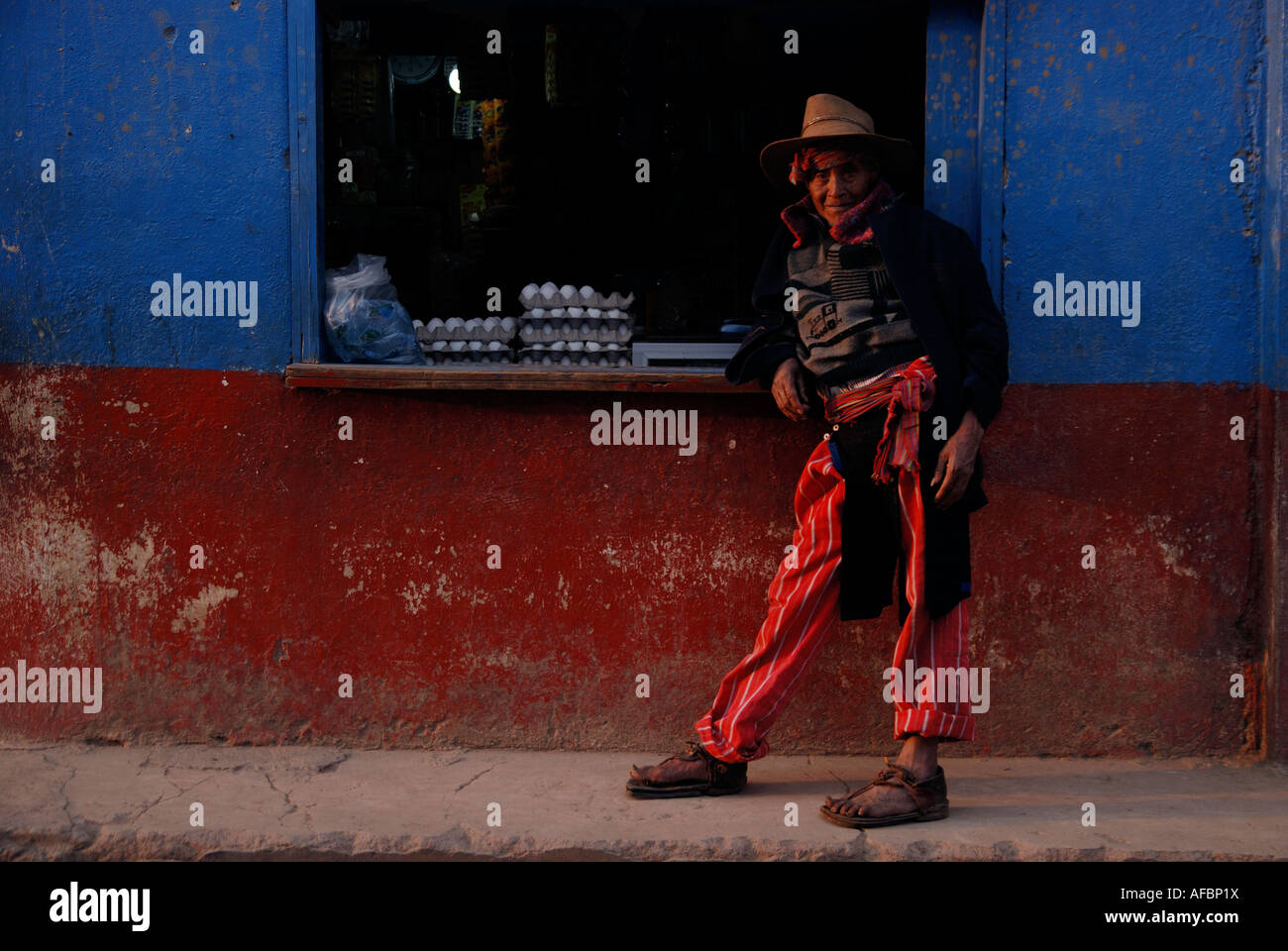 Mayan man dressed in the traditional local costume leaning on shop ...