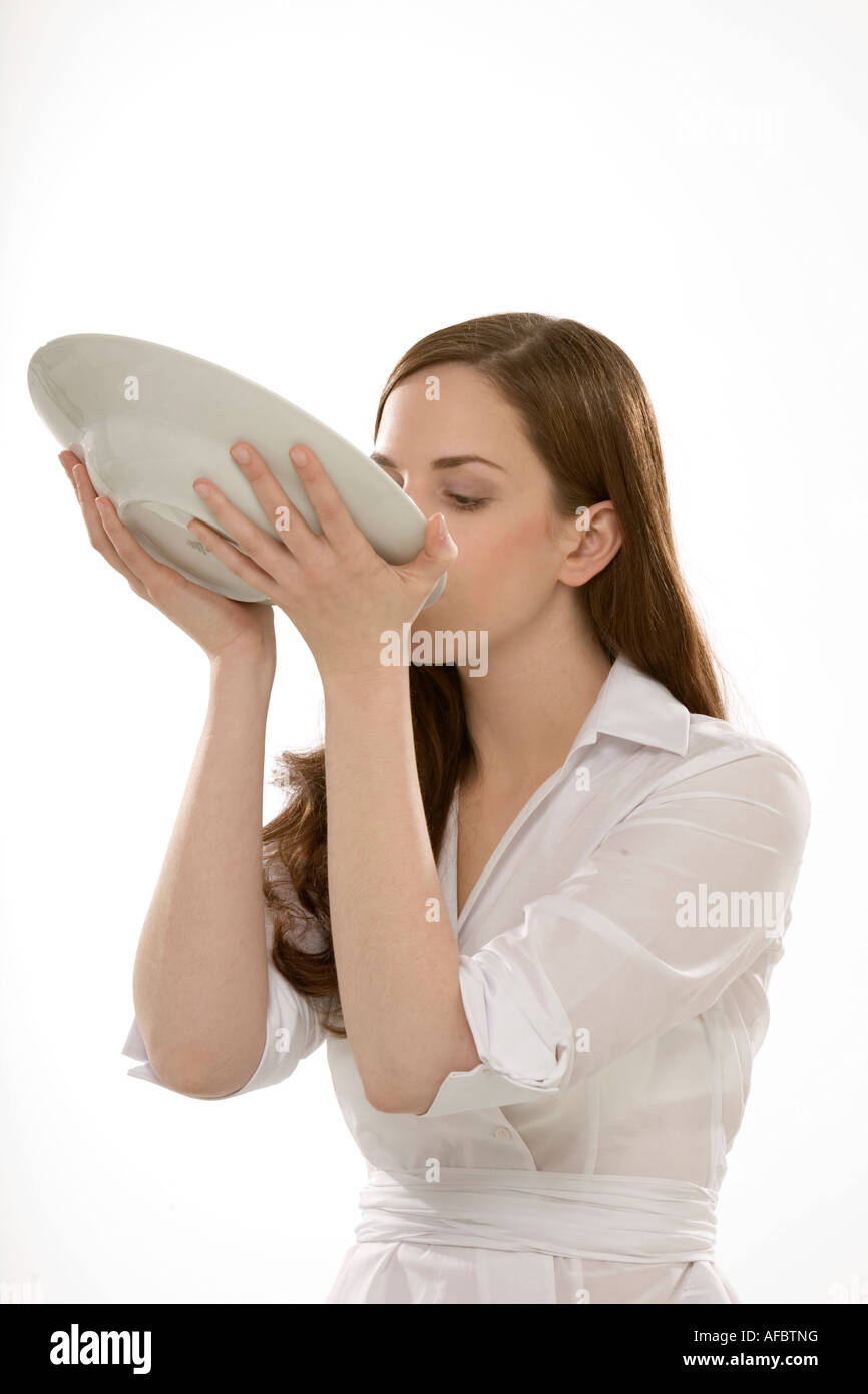 Young woman drinking from plate, portrait Stock Photo - Alamy