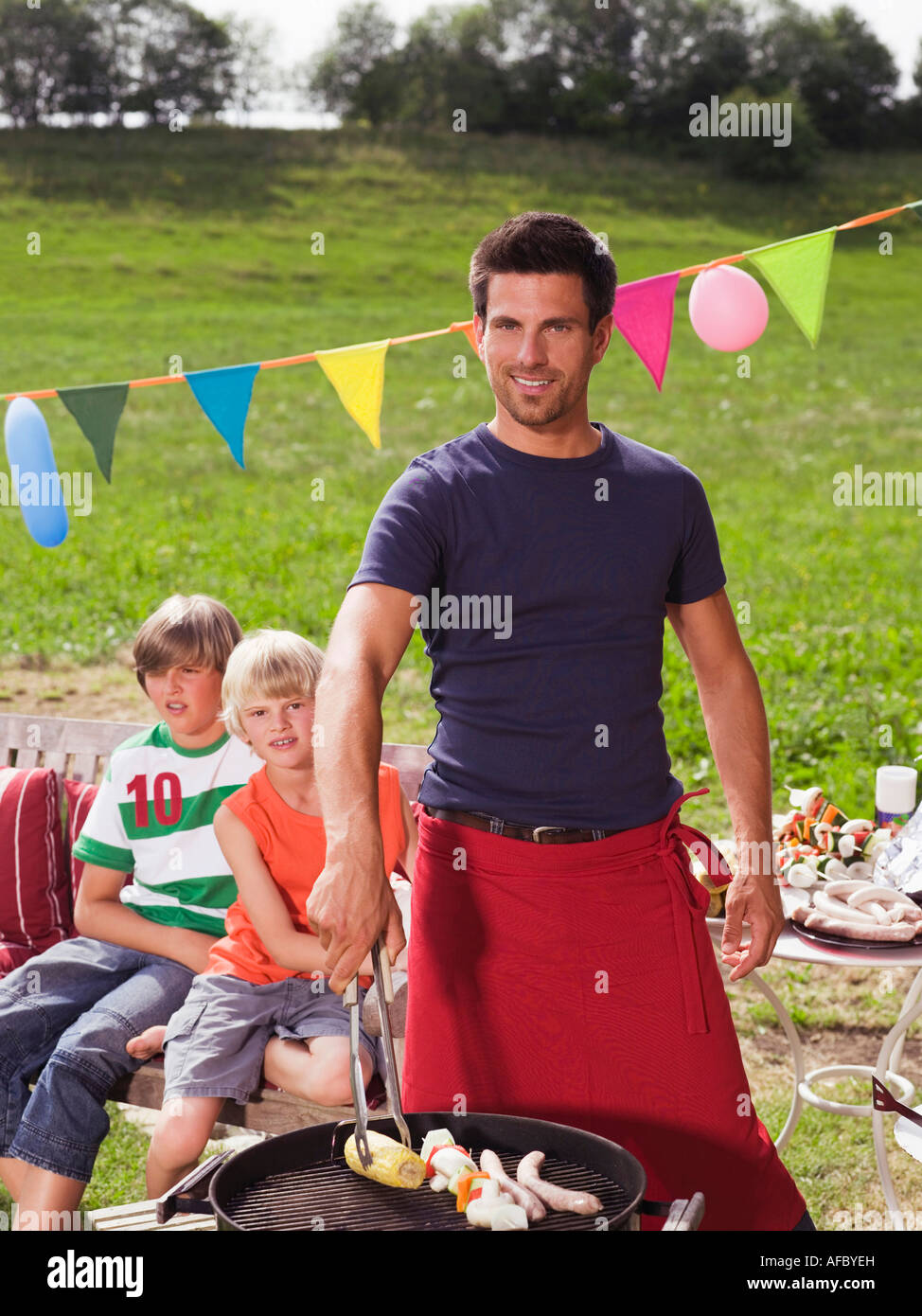 Father preparing barbecue, children in background Stock Photo - Alamy