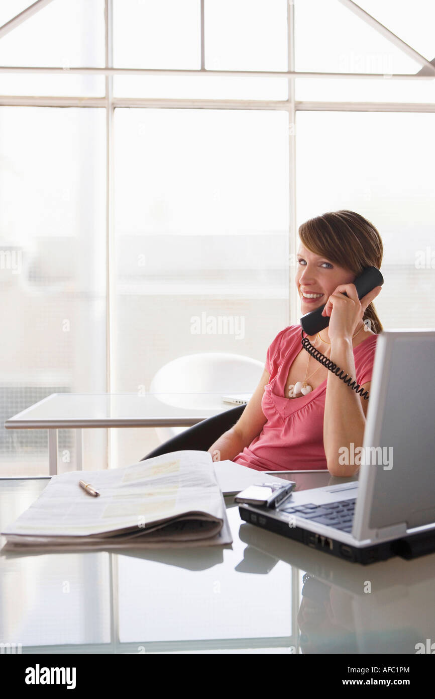 Woman at desk using phone Stock Photo - Alamy