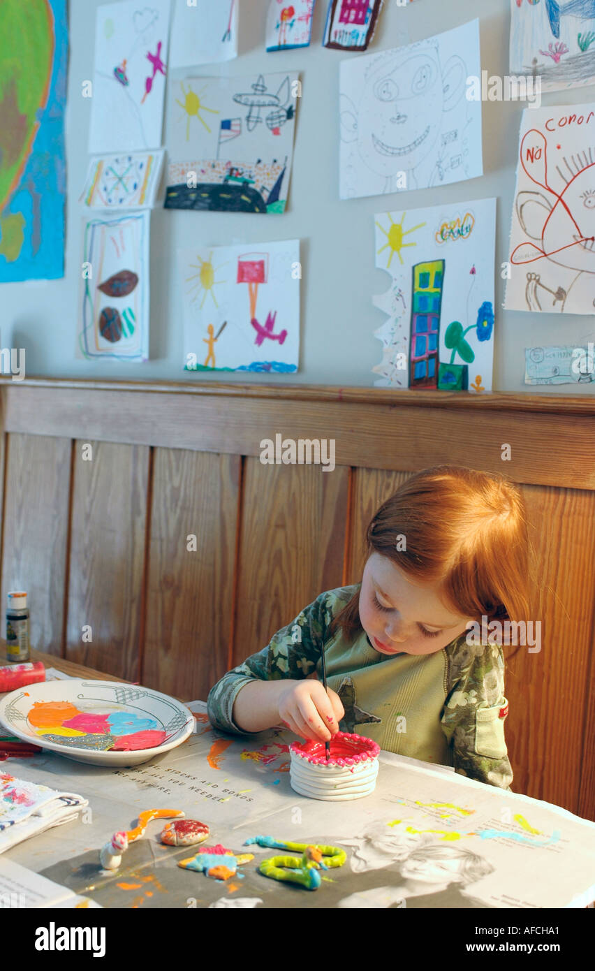 Portrait of a young four year old redhead girl child painting with her ...