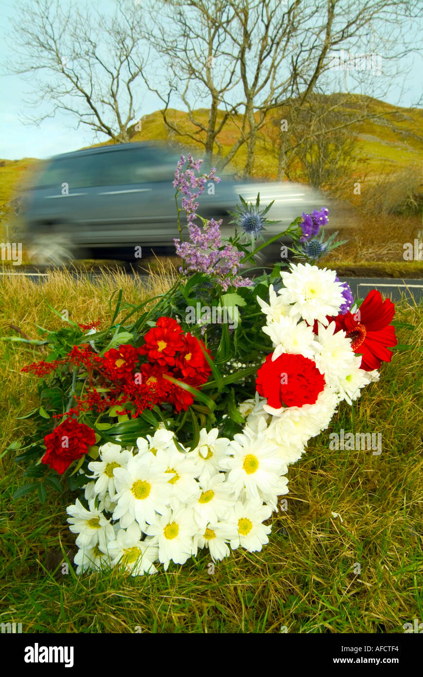 speeding car driving past flowers that have been placed to signify a ...