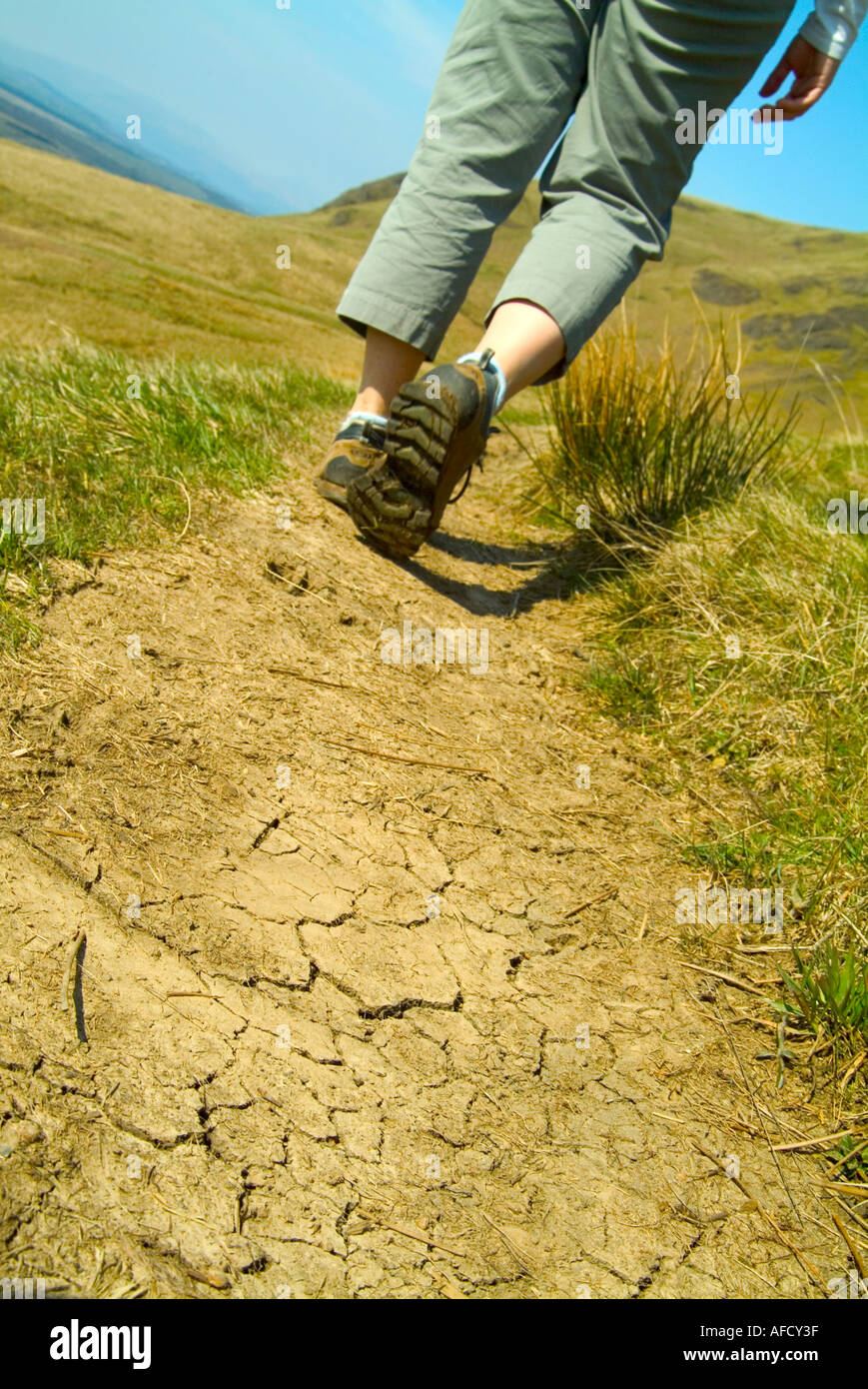 woman walking along dirt track badly damaged by erosion and over use ...