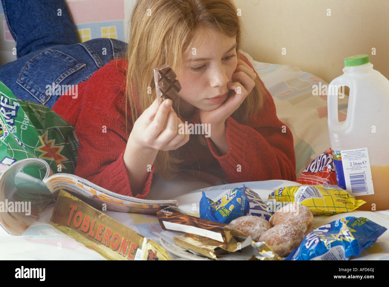 girl binge eating while reading a magazine Stock Photo - Alamy