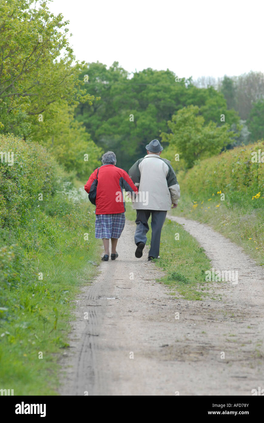 Retired couple walk together along a country lane Stock Photo - Alamy