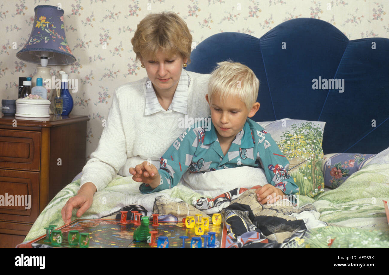 sick child in bed with mother playing a game with him Stock Photo - Alamy