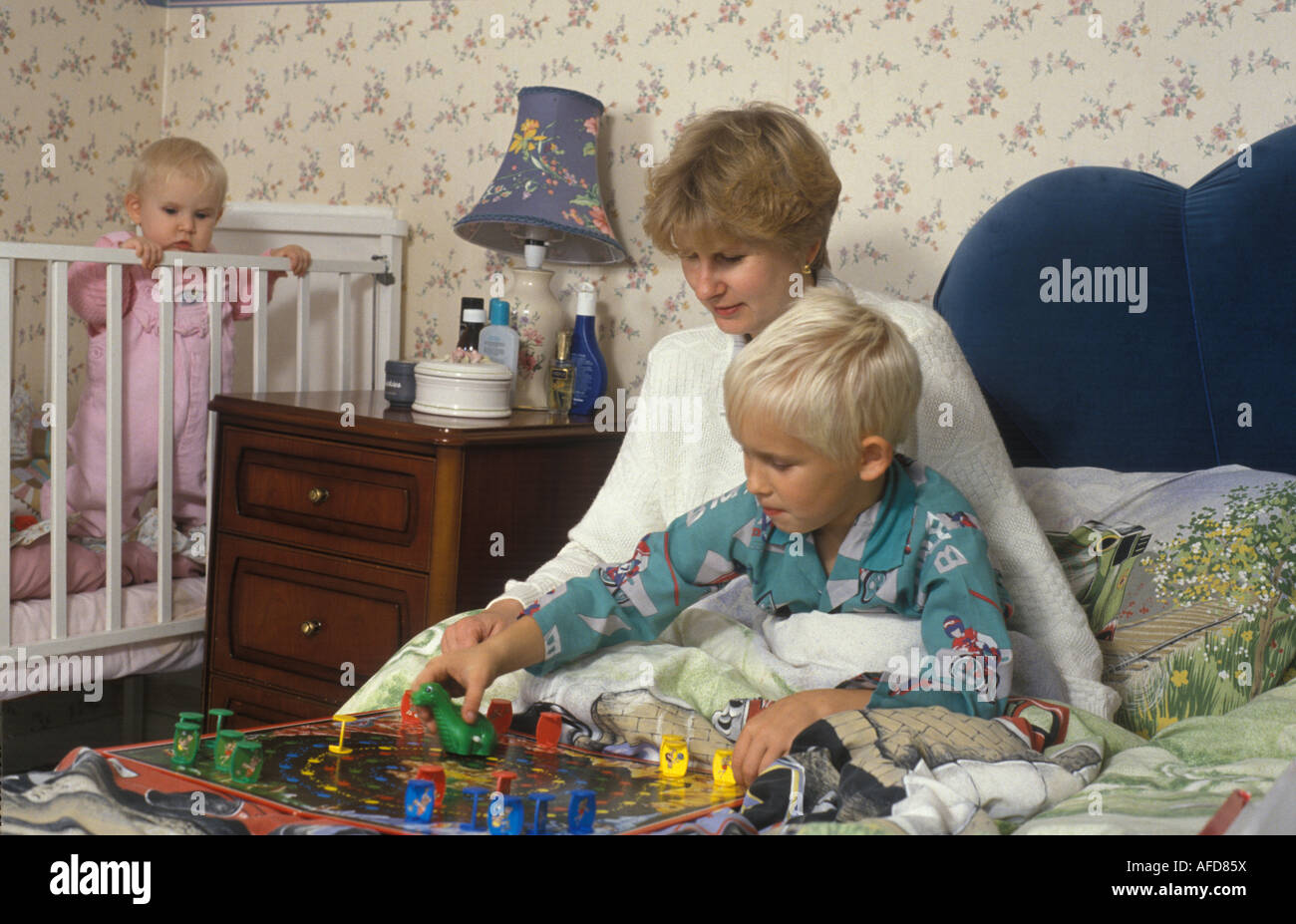 sick child in bed with mother playing a game with him Stock Photo - Alamy