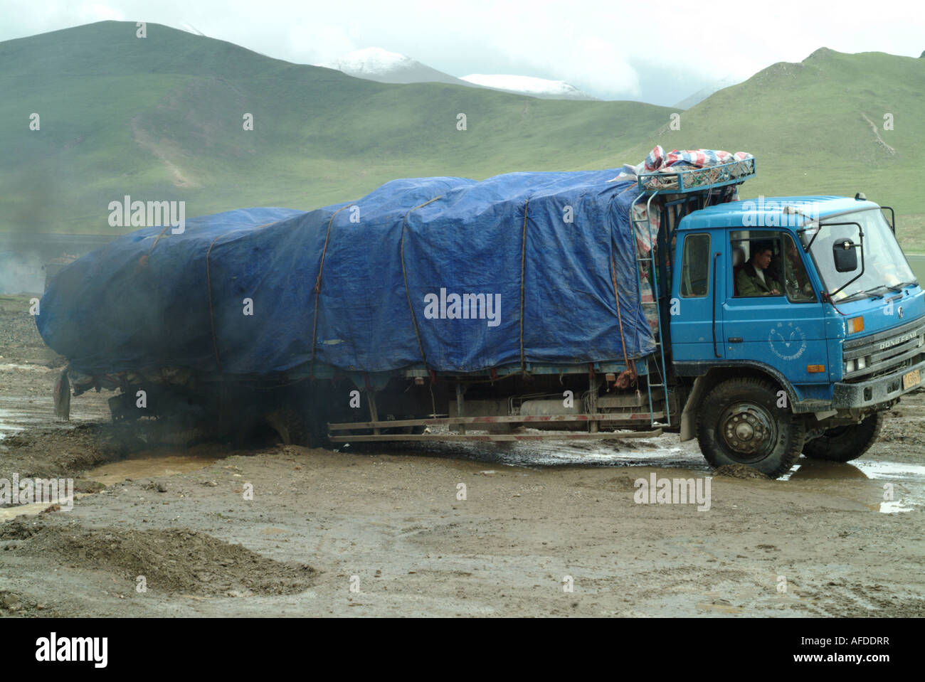 A truck gets bogged down in Tibet on a patch of road that resembles a ...