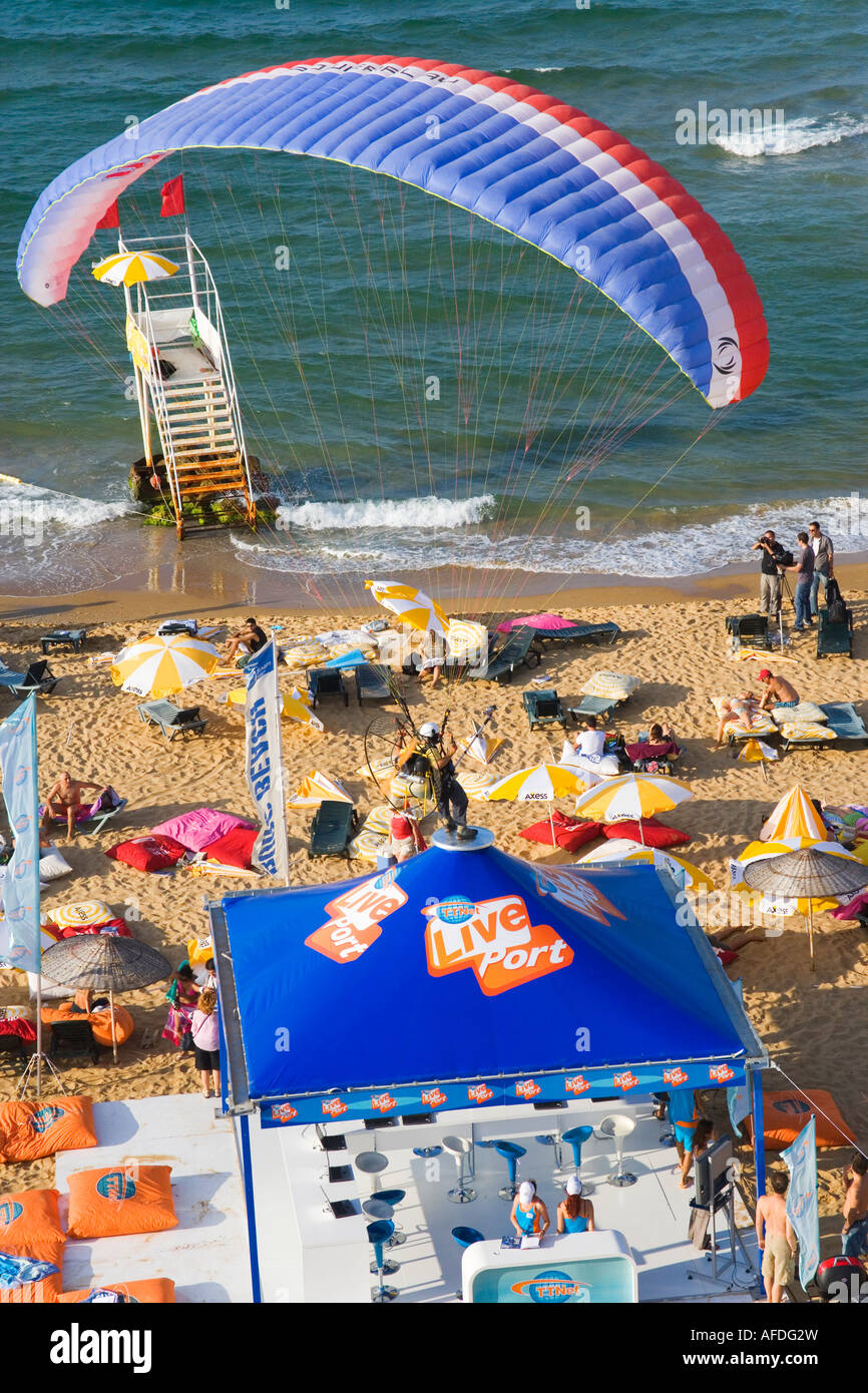 Powered paraglider flying over people enjoying the sun aerial Burc ...