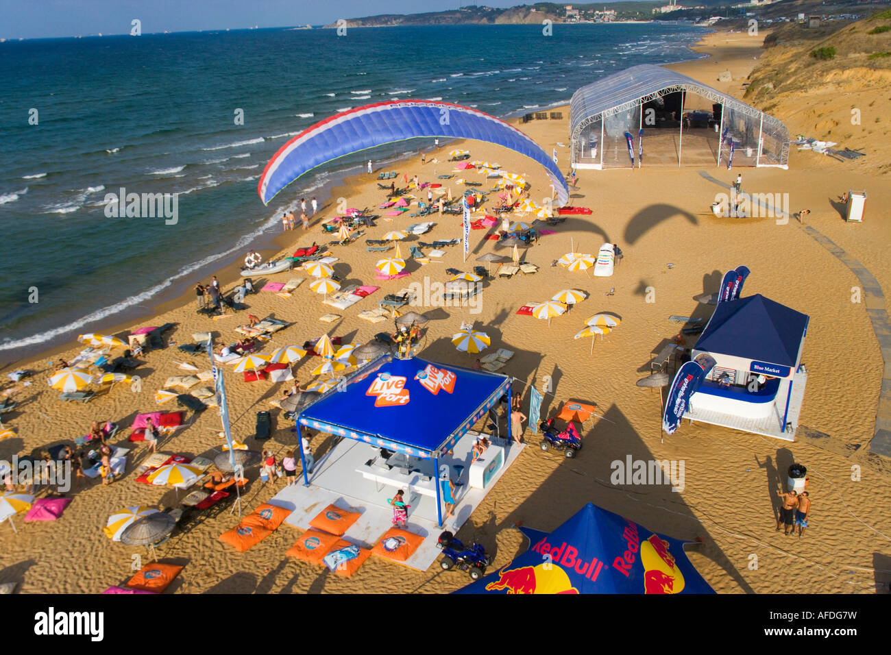 Powered paraglider flying over people enjoying the sun aerial Burc ...