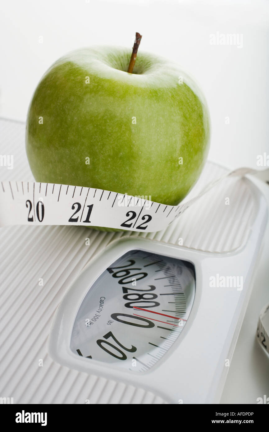 Apple and tape measure on a scale Stock Photo - Alamy
