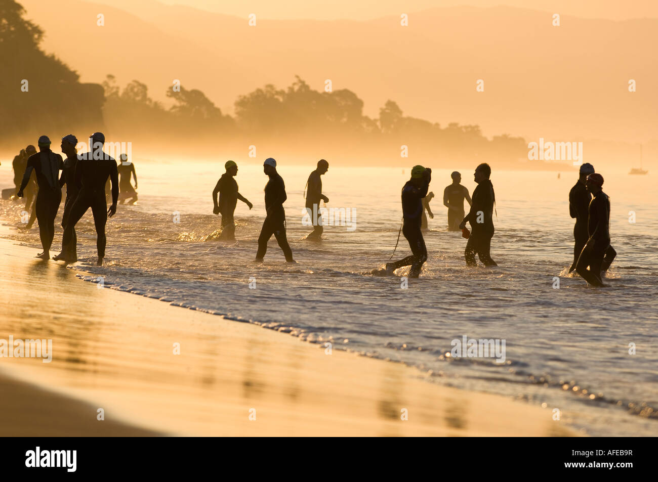 Silhouette of competitors warming up in ocean at dawn prior to race ...