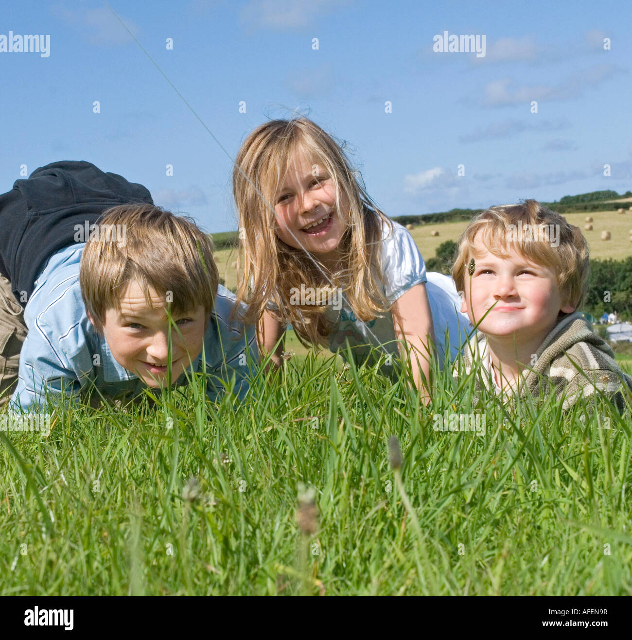 Three children playing in grass Stock Photo - Alamy