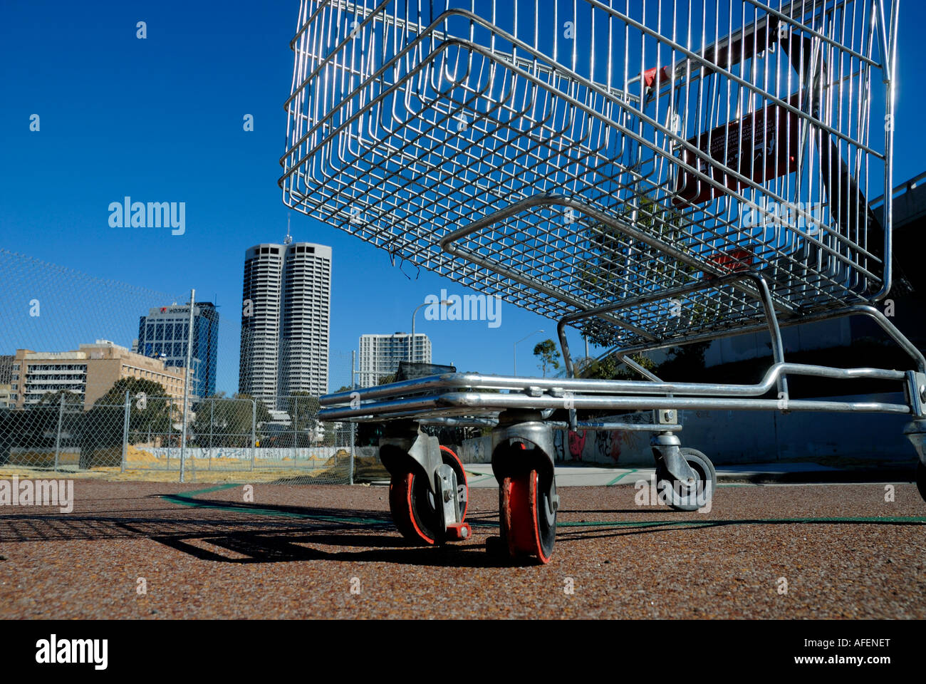 ground-level close up of shopping trolley, city visible in background ...