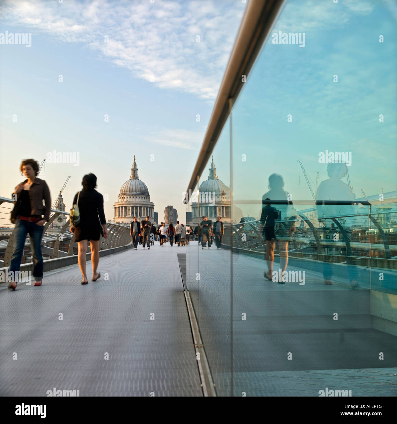 golden glow of pink sunset over woman and crowd crossing millennium ...