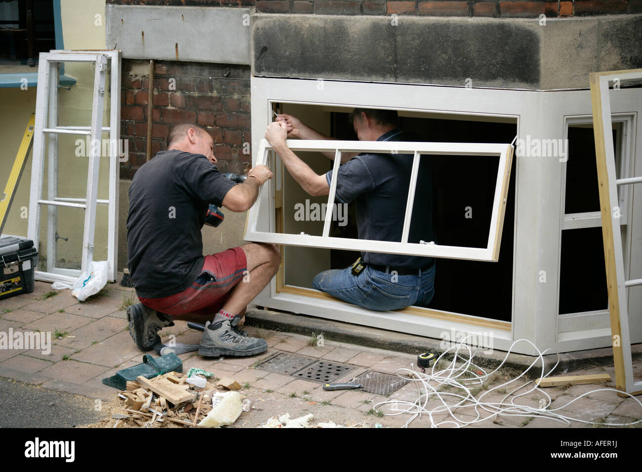 Tradesmen at work replacing a sash window in a basement flat, Saffron ...