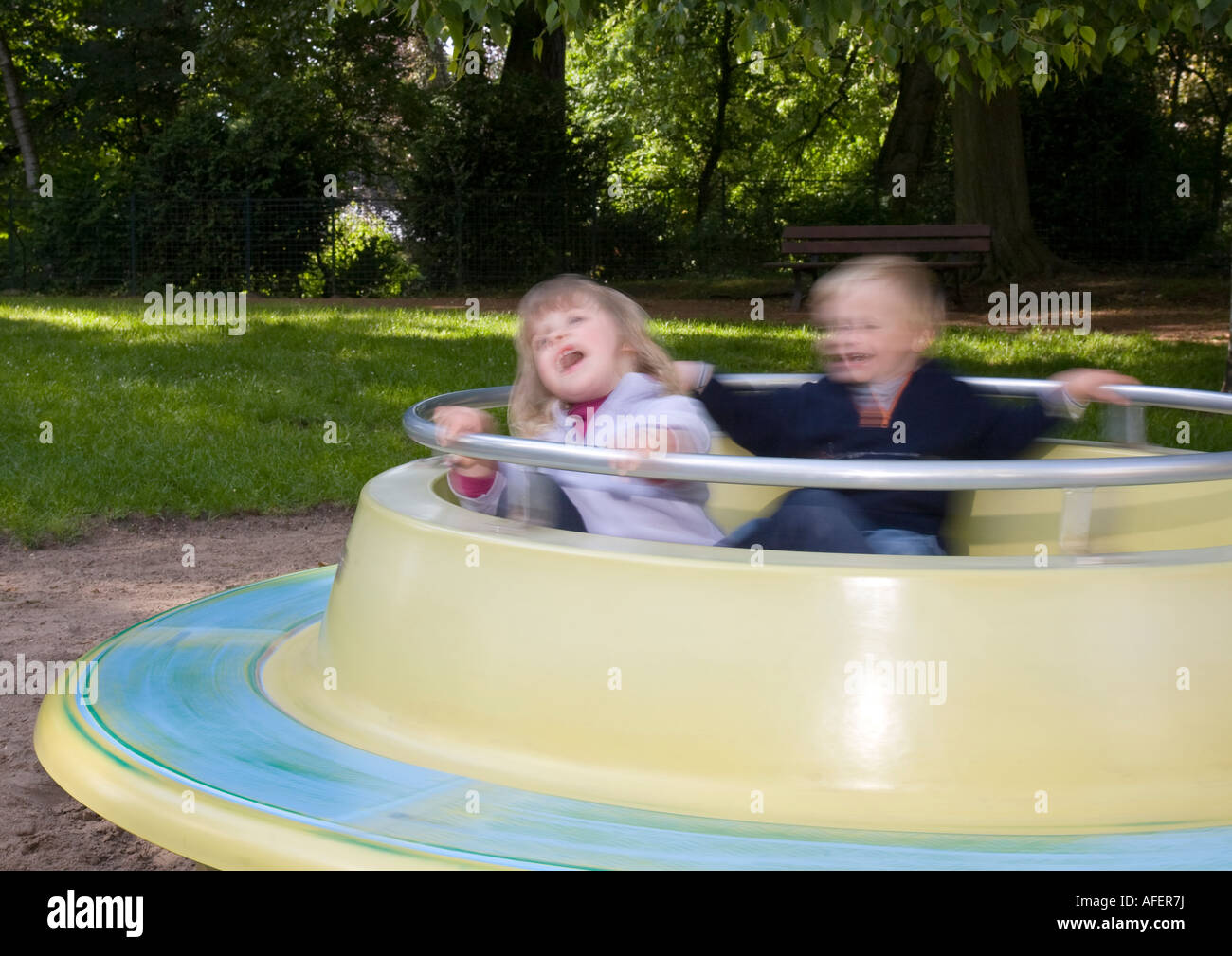 two children on a roundabout in the park Stock Photo - Alamy