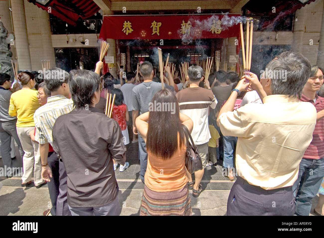 People holding burning incense stick praying in front of a Chinese ...