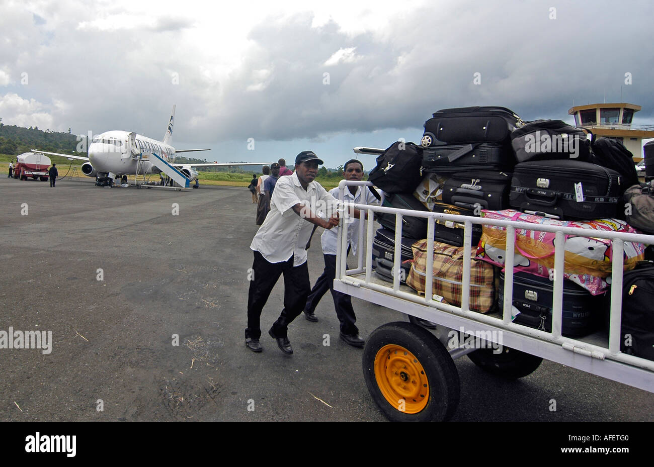 A man pushing a trailer full of luggages on the tarmac of the Manokwari ...