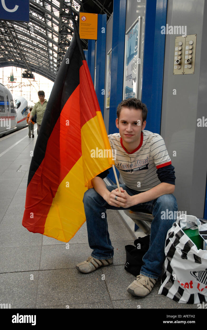 A young German fan with flag waiting for a train at Cologne Station ...