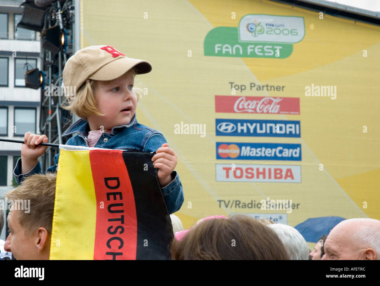 A young child with a German flag sits on her fathers shoulders at the ...