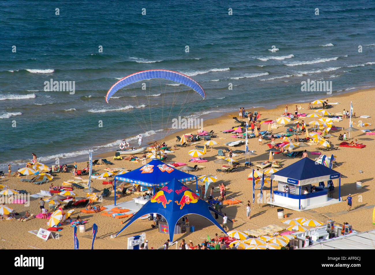 Powered paraglider flying over people enjoying the sun aerial Burc ...