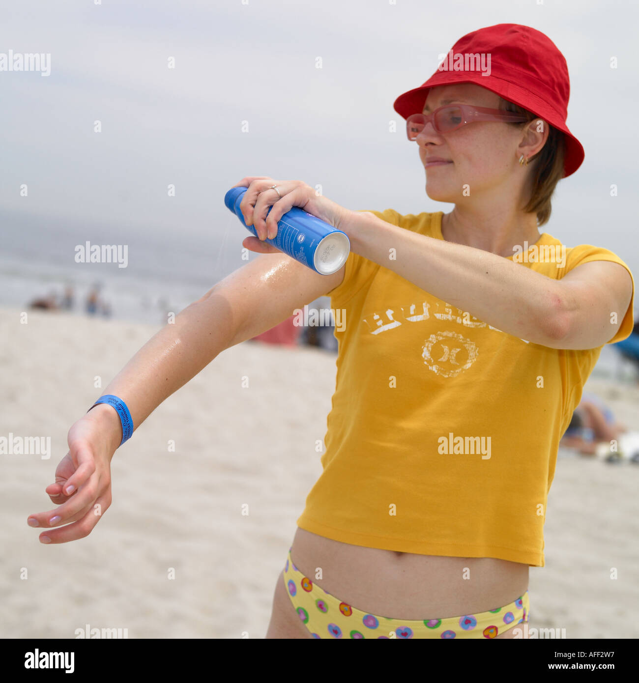 young woman in yellow swimsuit spraying sunscreen Stock Photo - Alamy