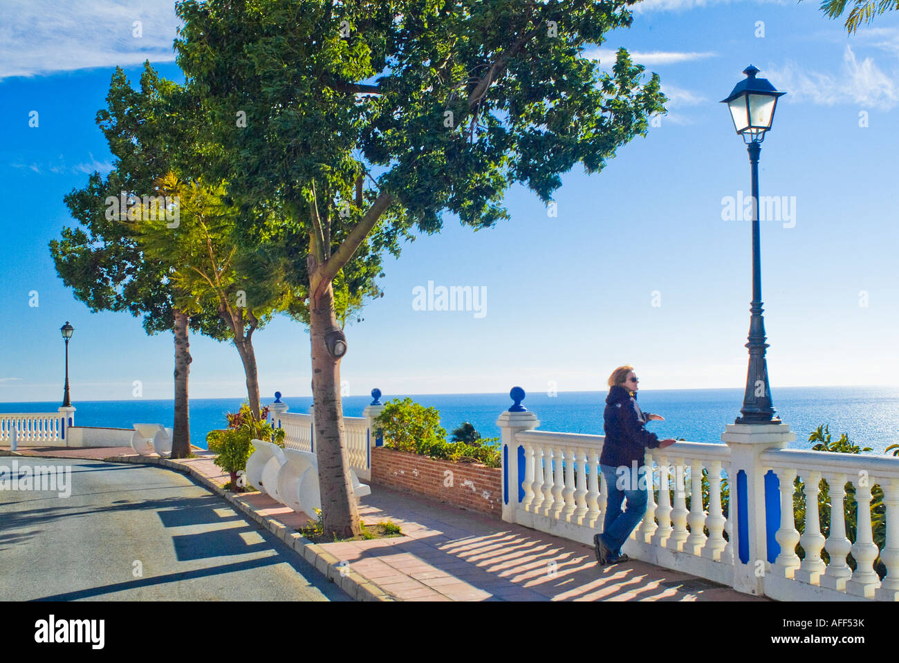 Female tourist standing on walkway in Maro Spain viewing the ocean ...