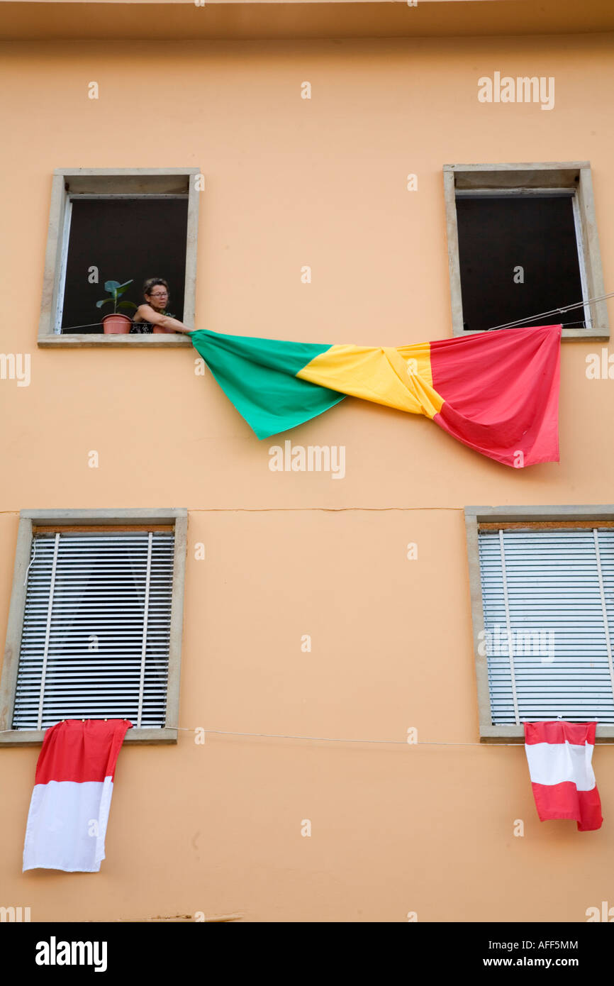 Woman straightening flags on balconies in Porto Santo Stefano Monte ...